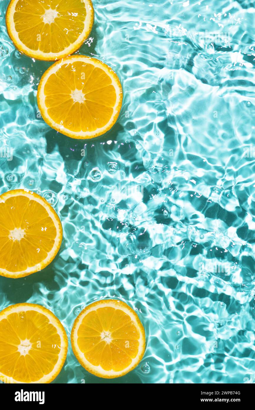 Creative summer background with orange fruit slices in swimming pool ...