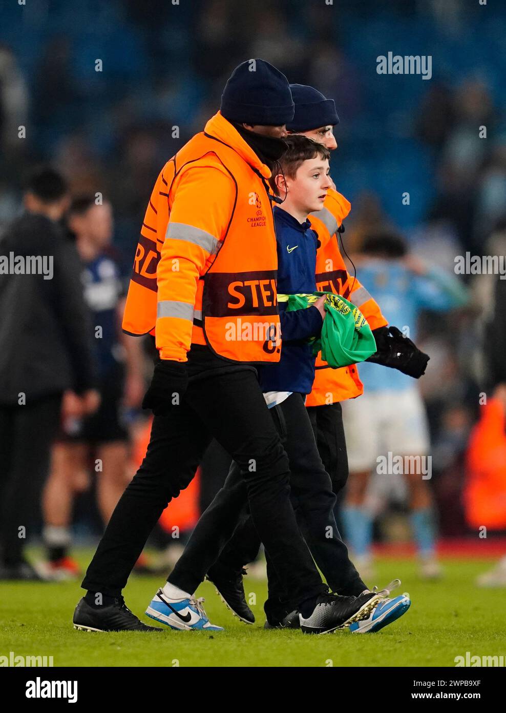 A young fan who ran onto the pitch is lead away after receiving a shirt ...