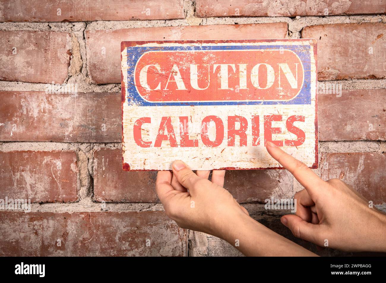 Calories. Caution sign in a woman's hand on a brick background Stock ...