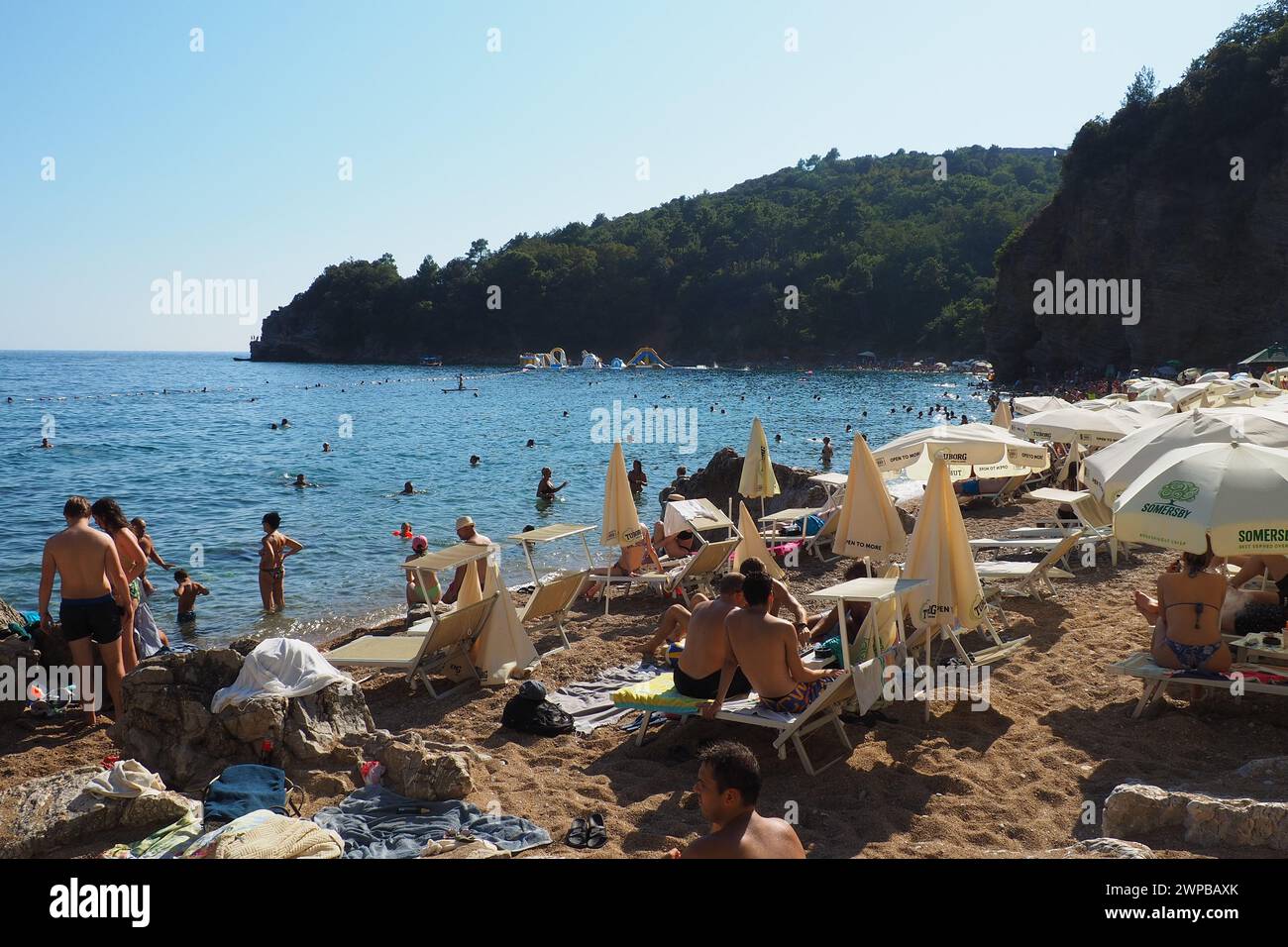 Budva, Montenegro, Mogren beach. August 15 2022 Sand and pebble beach near high cliffs. Beach ...