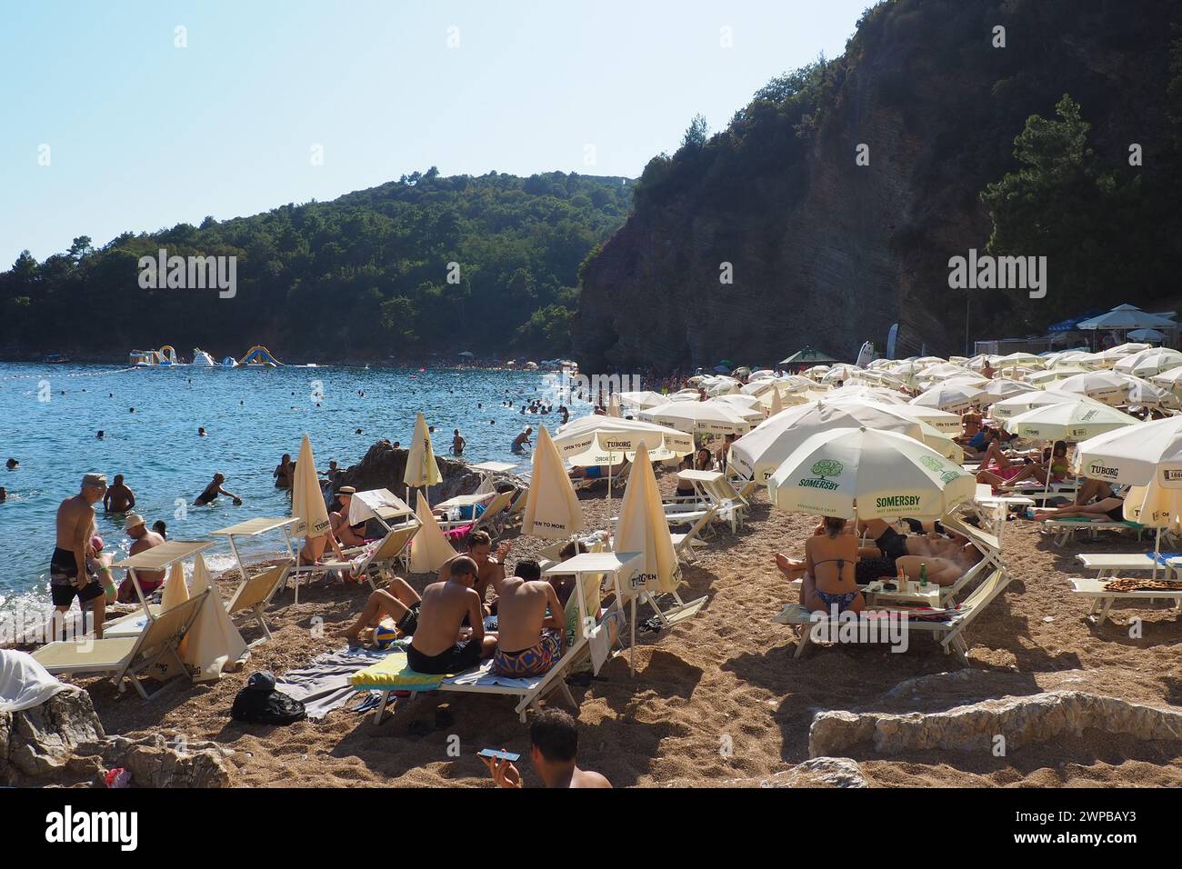 Budva, Montenegro, Mogren beach. August 15 2022 Sand and pebble beach near high cliffs. Beach ...
