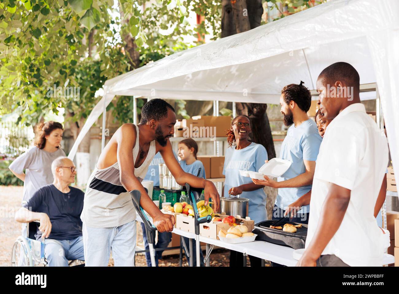 Caring charity workers serve warm meals to the less privileged outdoors ...