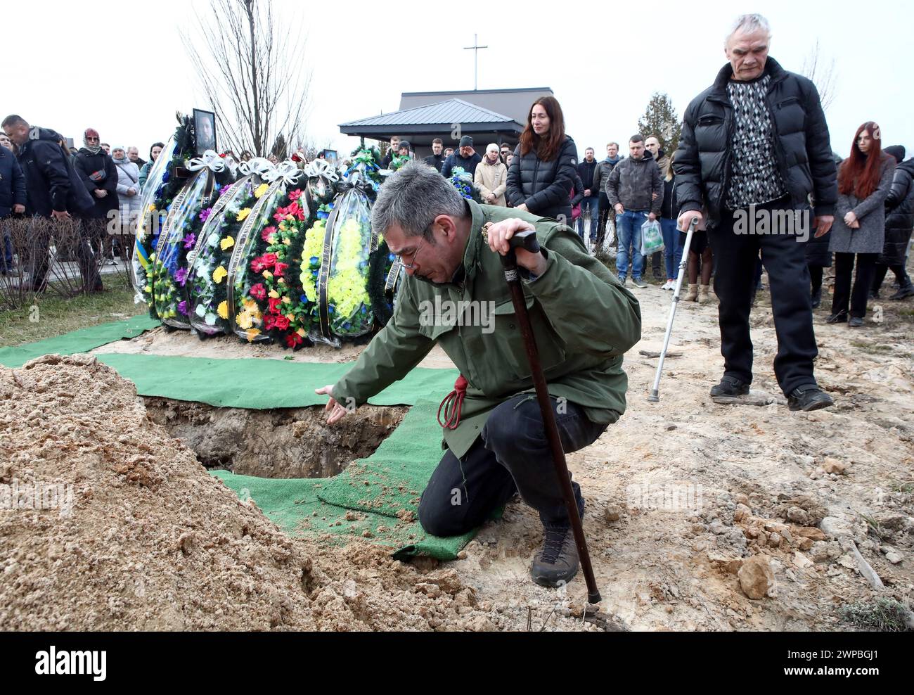 Non Exclusive: BUCHA, UKRAINE - MARCH 5, 2024 - A mourner throws soil ...