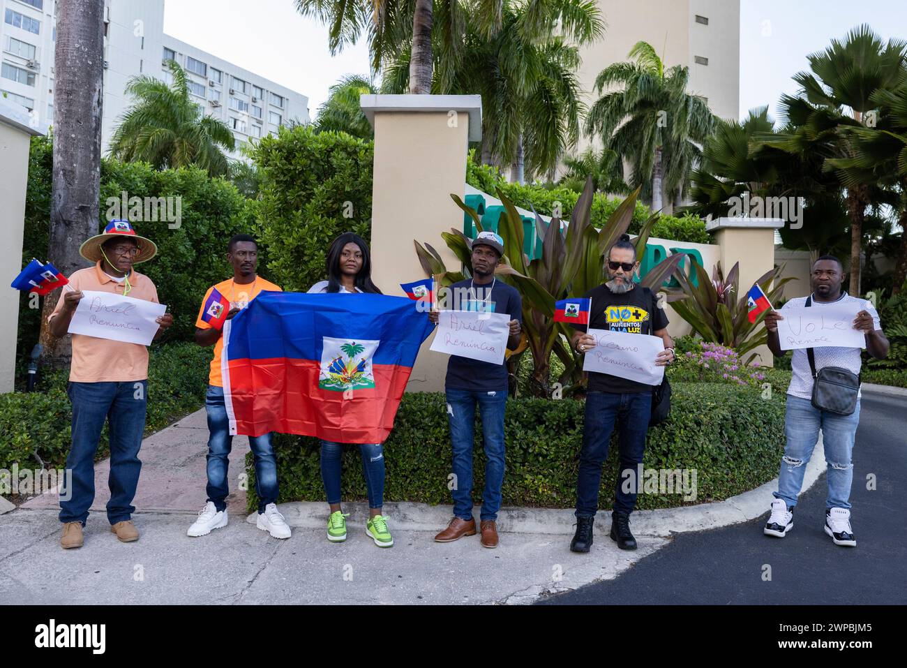 Protesters holding Haitian national flags and handmade signs with ...