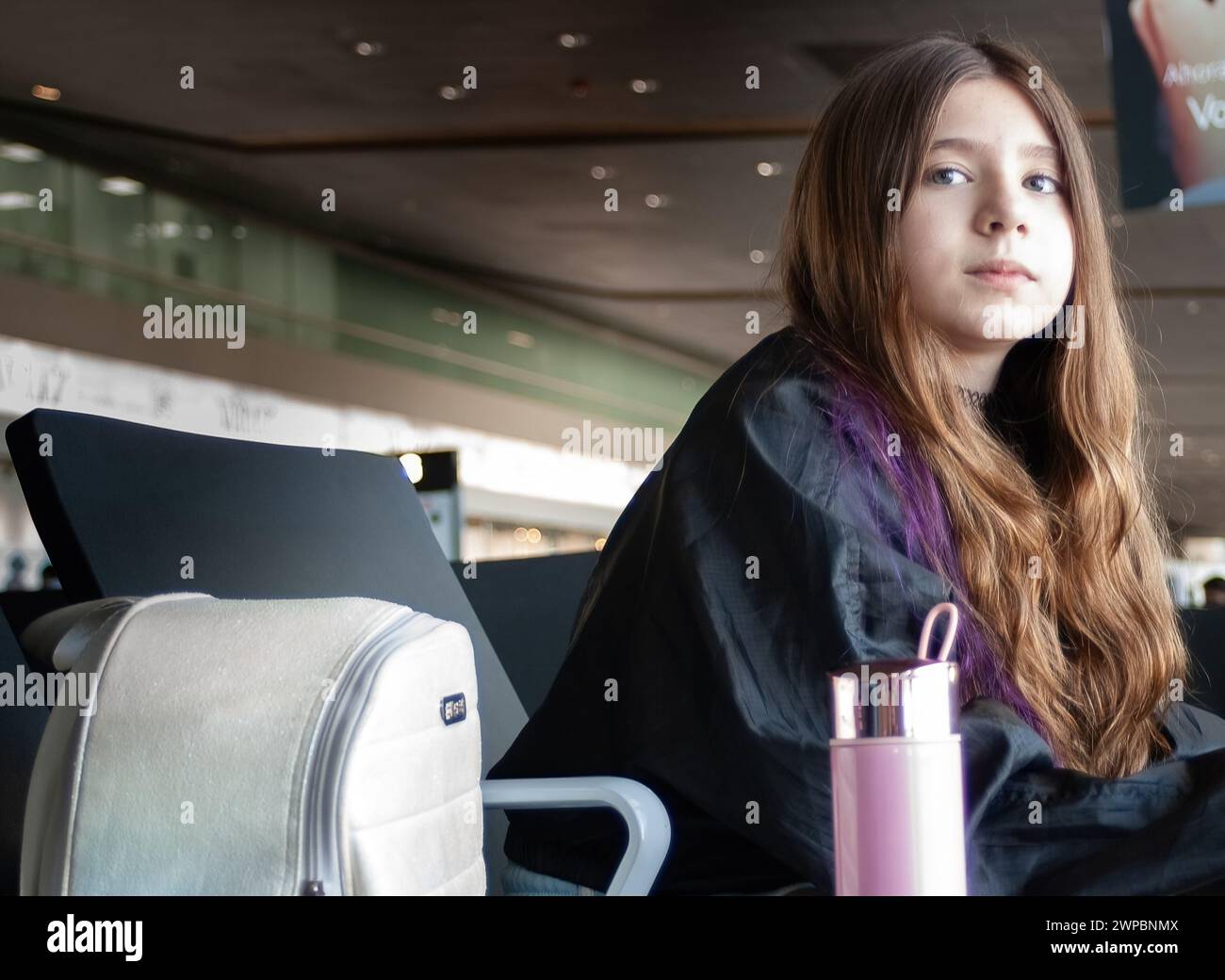 Young girl looks off into the distance during a stopover at the airport ...