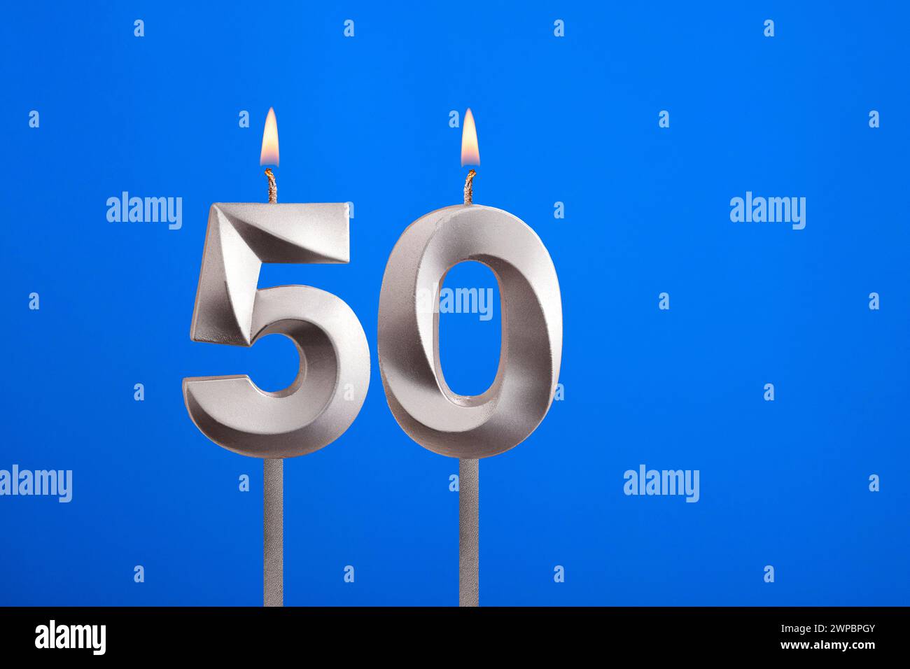 Birthday number 50 - Candle lit on blue background Stock Photo - Alamy