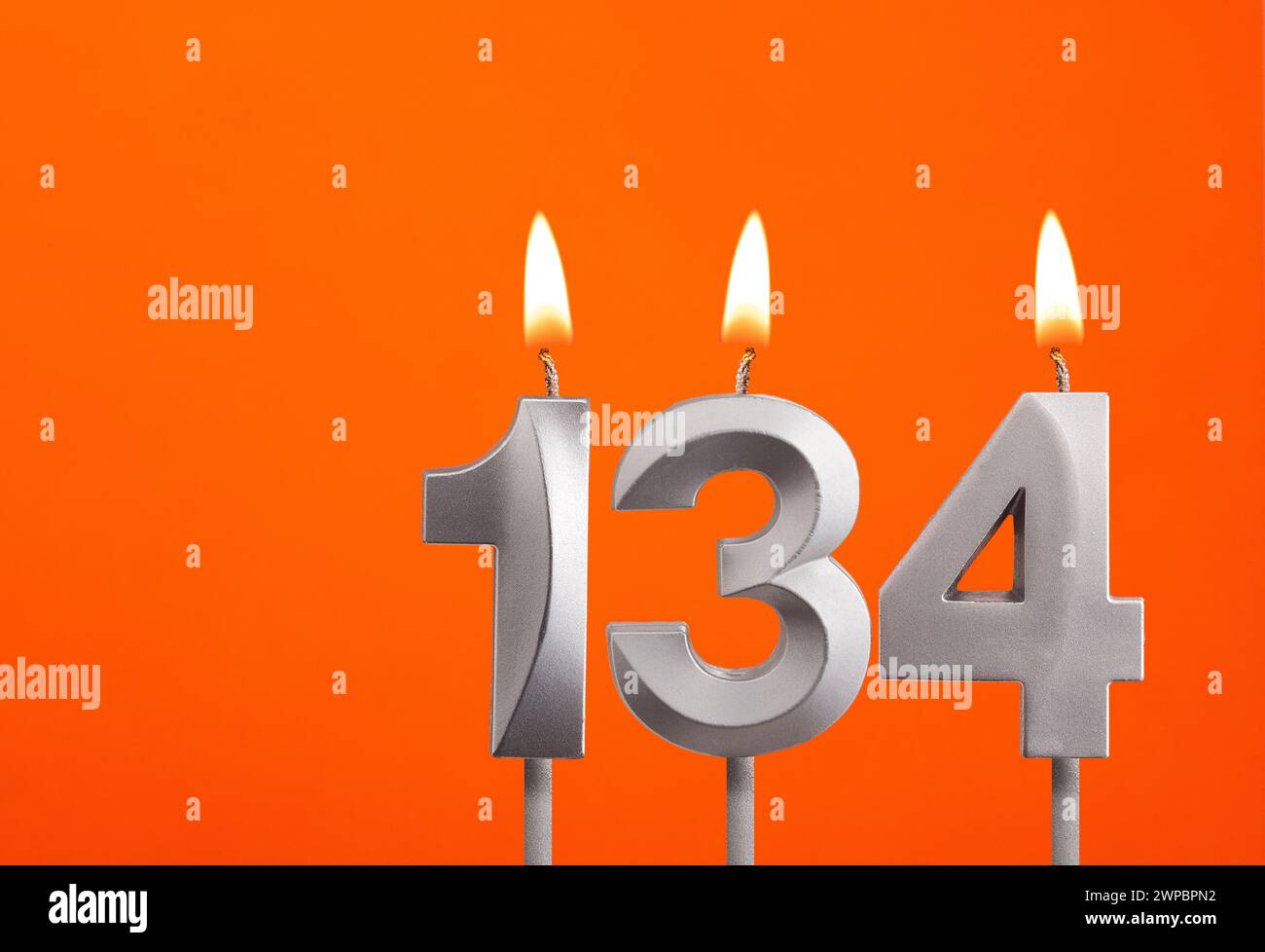 Candle number 134 - Birthday in orange background Stock Photo - Alamy