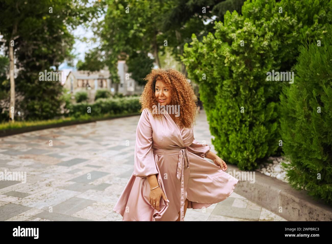 Young beautiful African American woman enjoys a walk in the summer ...
