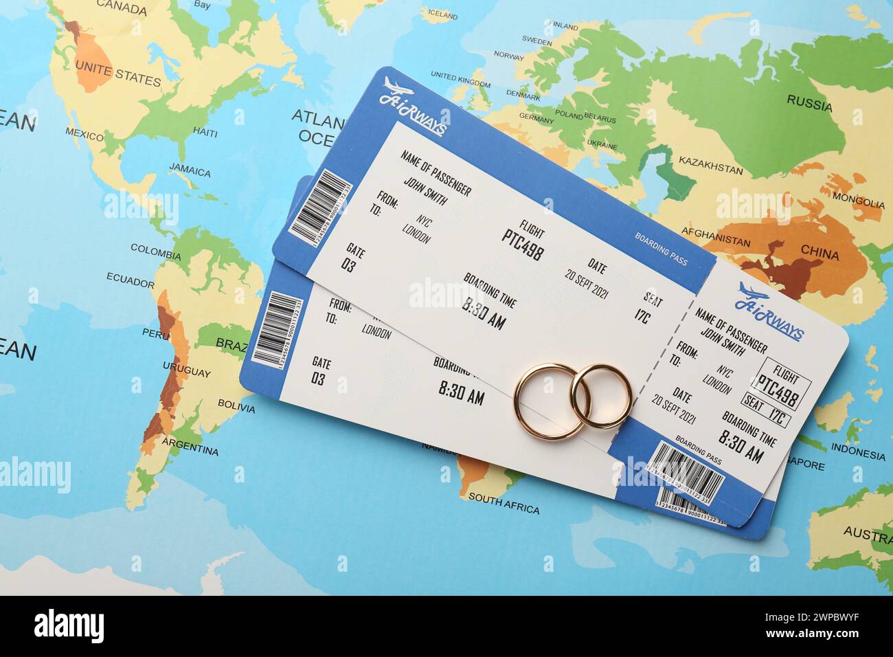 Honeymoon concept. Plane tickets and golden rings on world map, top ...