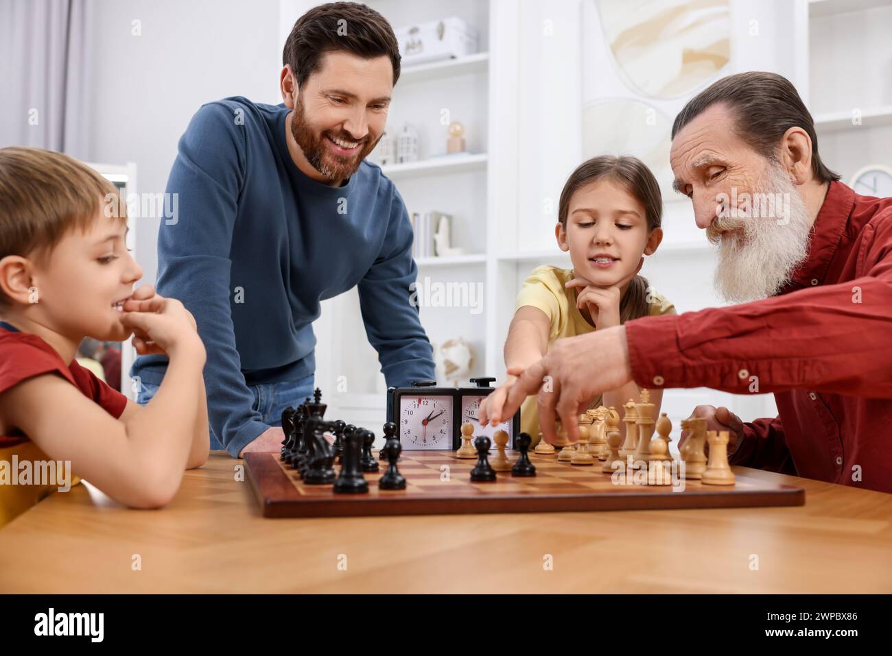 Family playing chess together at table in room Stock Photo - Alamy