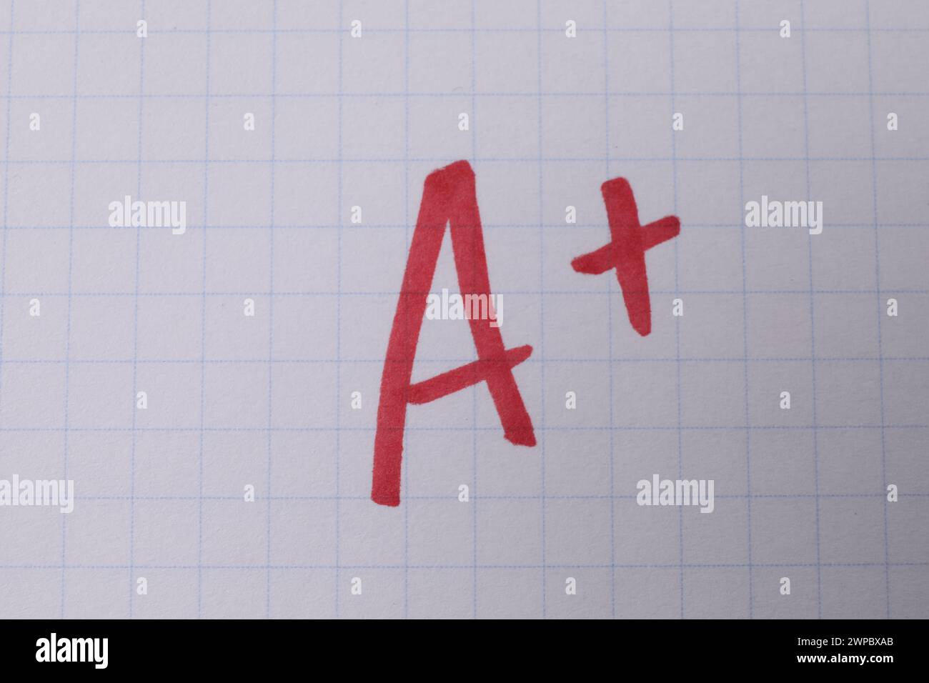 School grade. Red letter A with plus symbol on notebook paper, top view ...