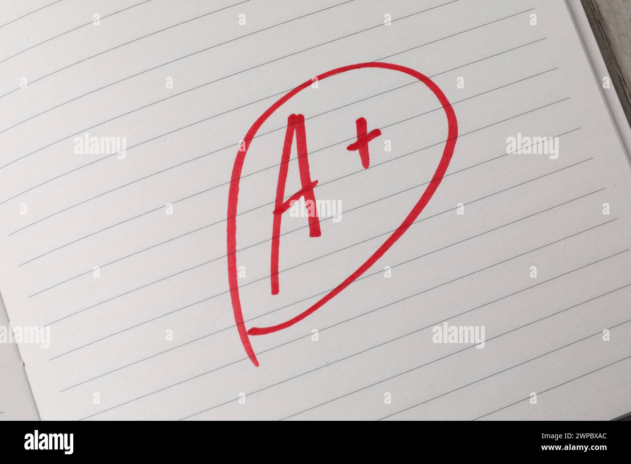School grade. Red letter A with plus symbol on notebook paper, top view ...