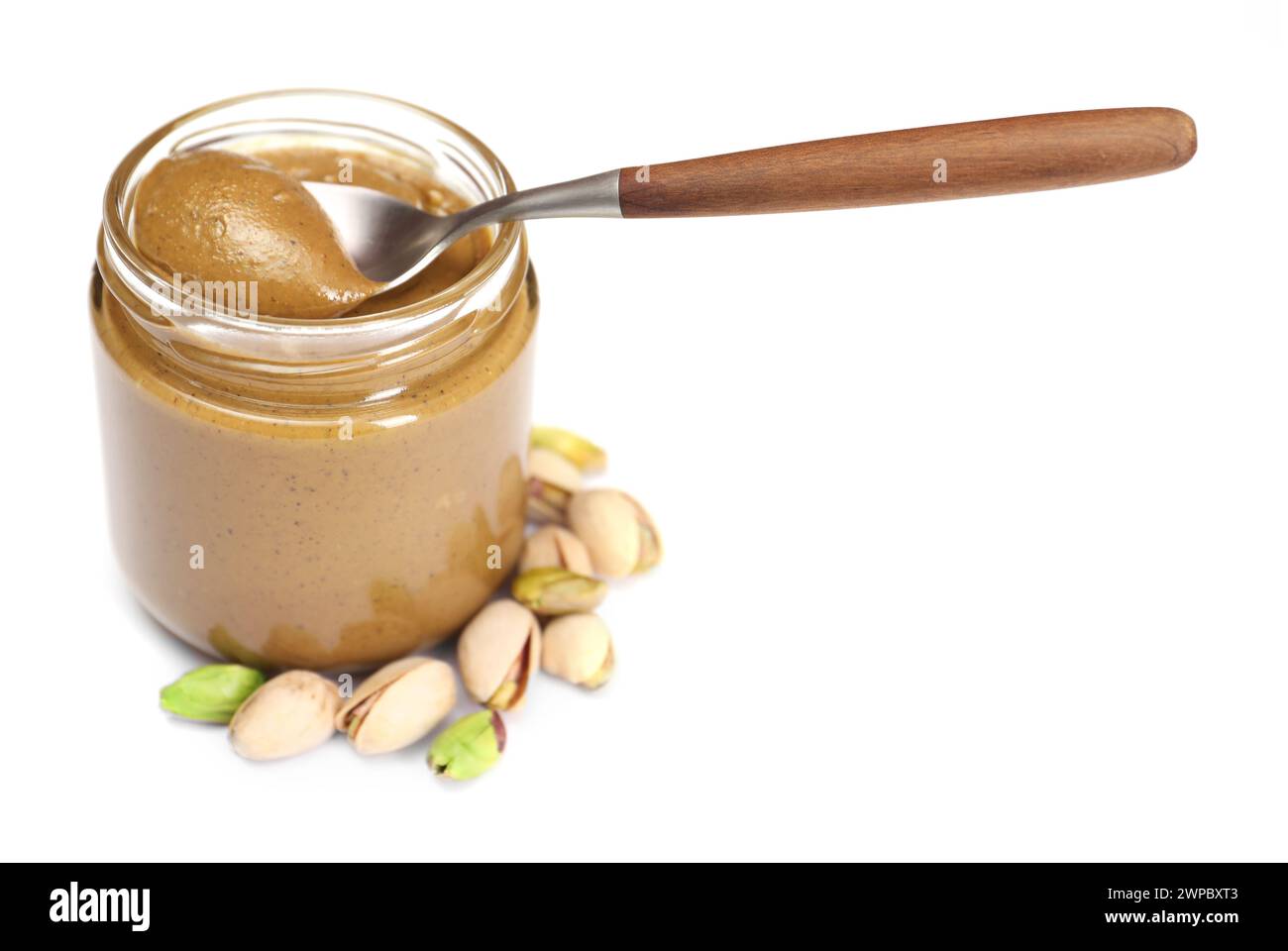 Tasty nut paste in jar, spoon and pistachios isolated on white Stock ...