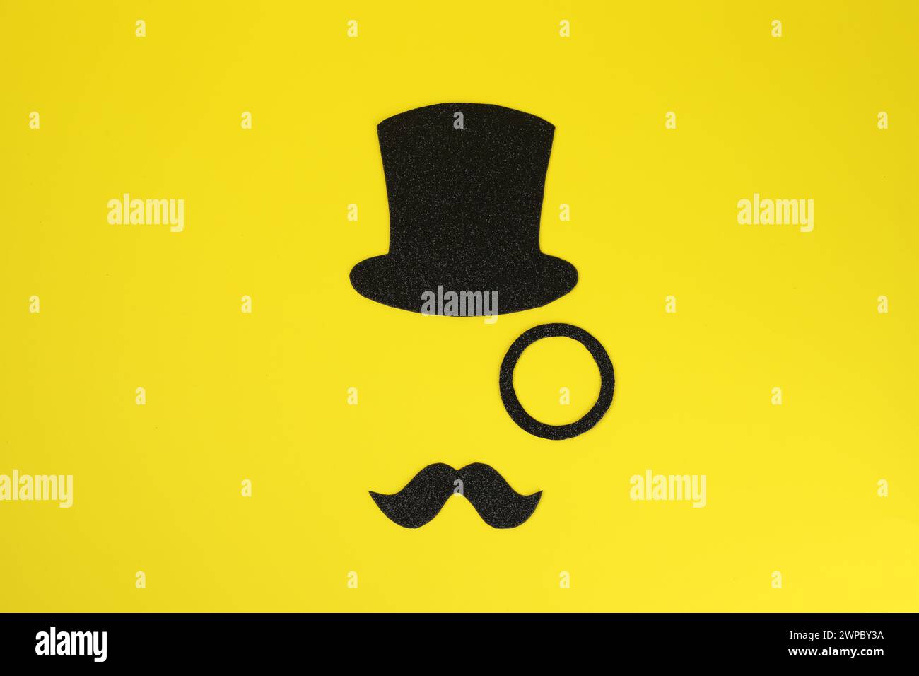Man's face made of fake mustache, hat and monocle on yellow background ...
