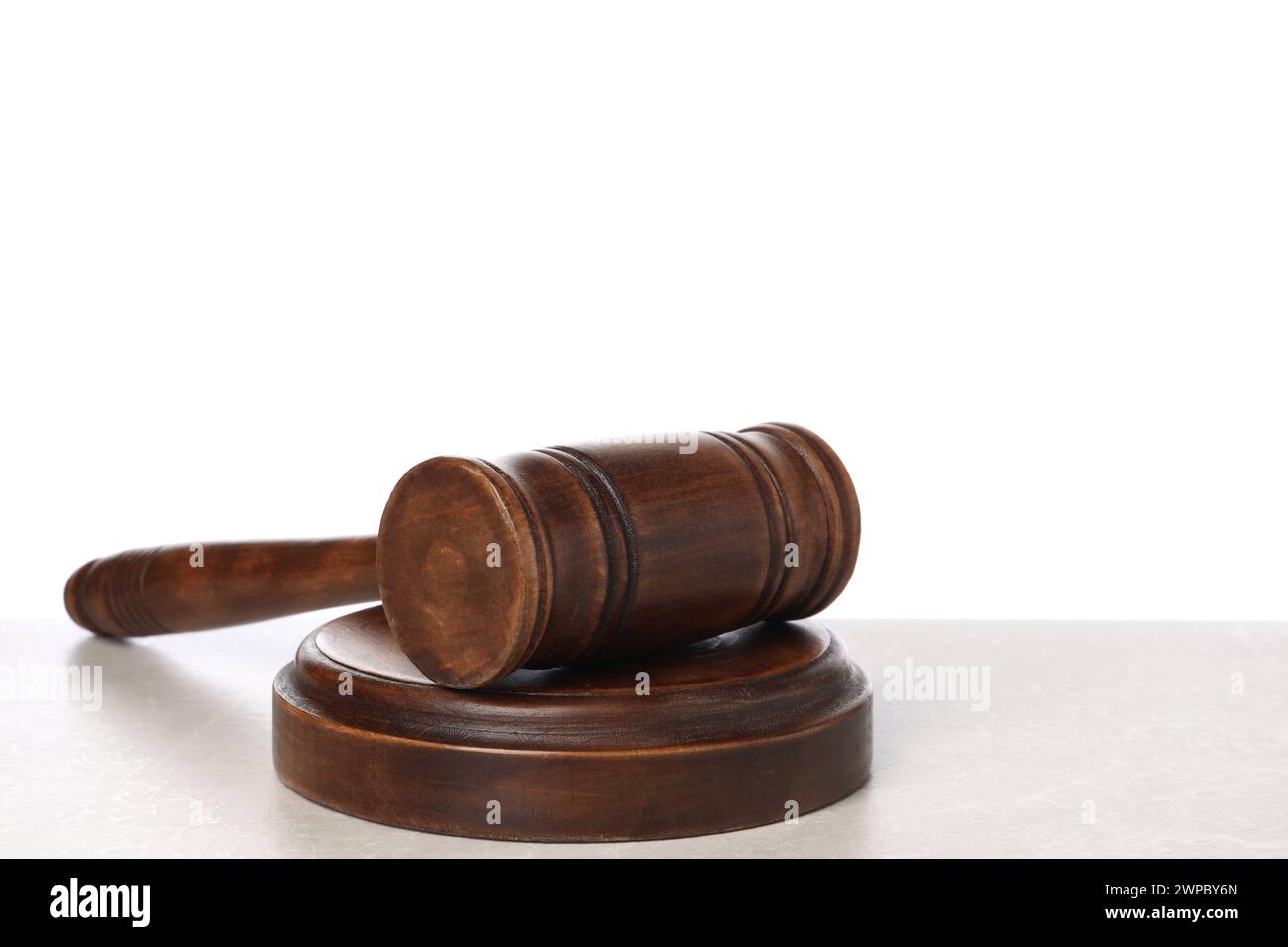 Wooden gavel on light table against white background. Space for text ...