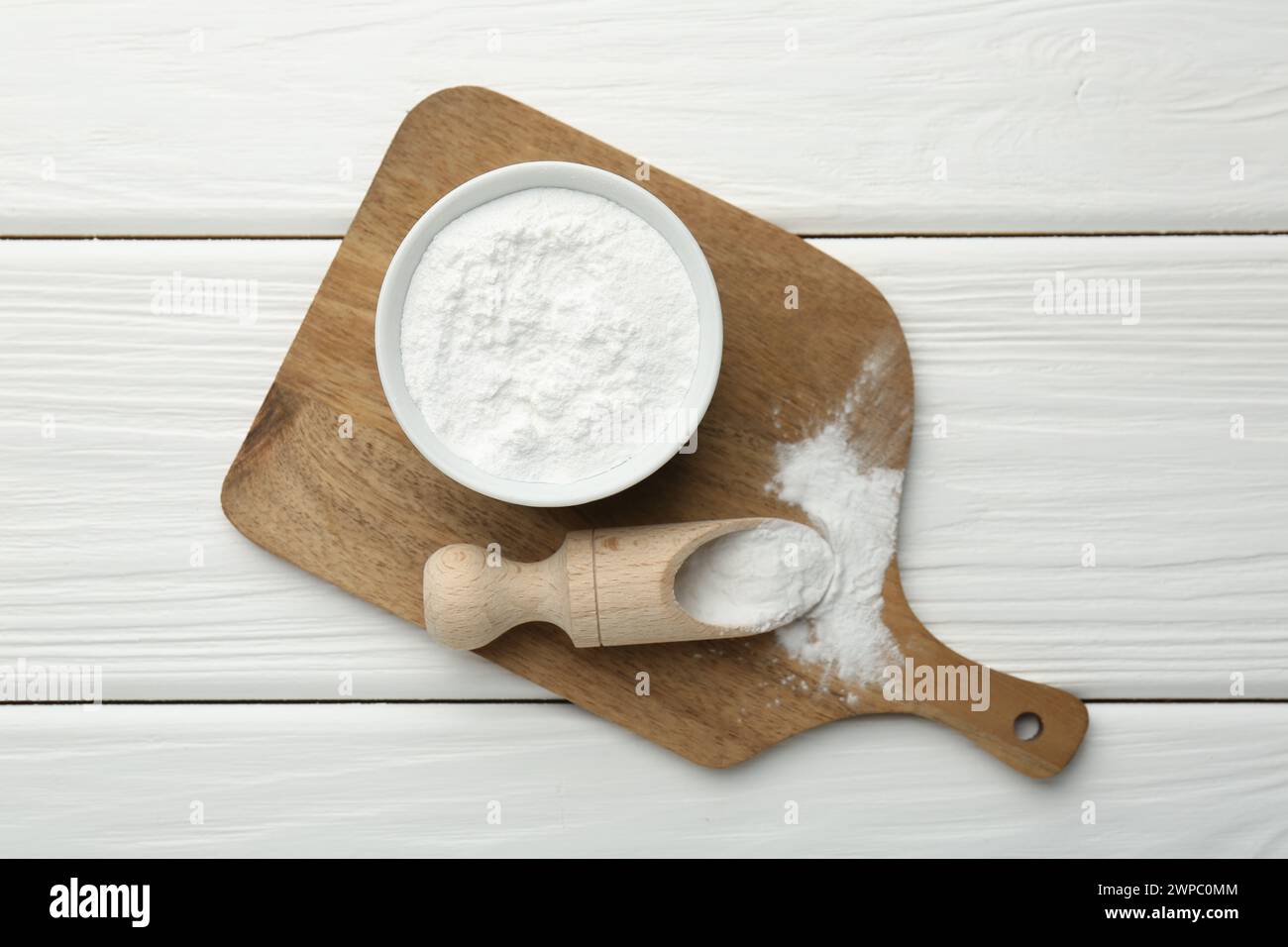 Baking powder in bowl and scoop on white wooden table, top view Stock ...