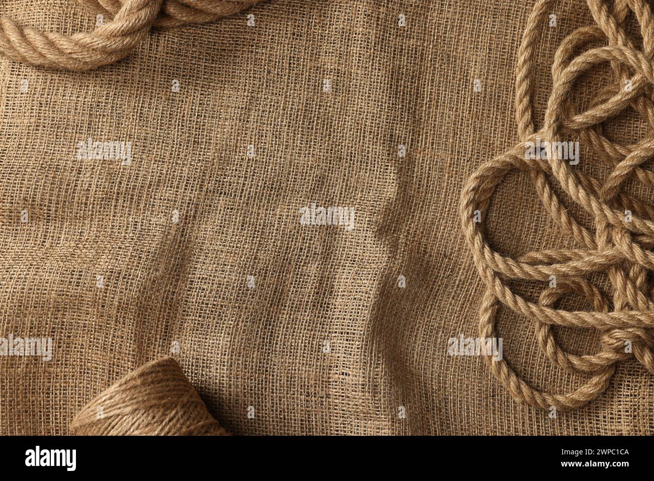 Spool of thread and natural brown jute on burlap fabric, top view Stock ...
