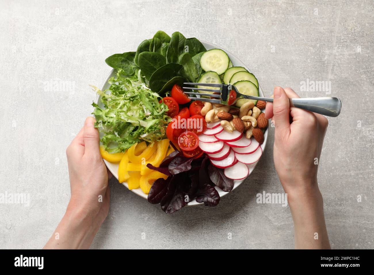 Balanced diet and vegetarian foods. Woman eating dinner at grey table ...