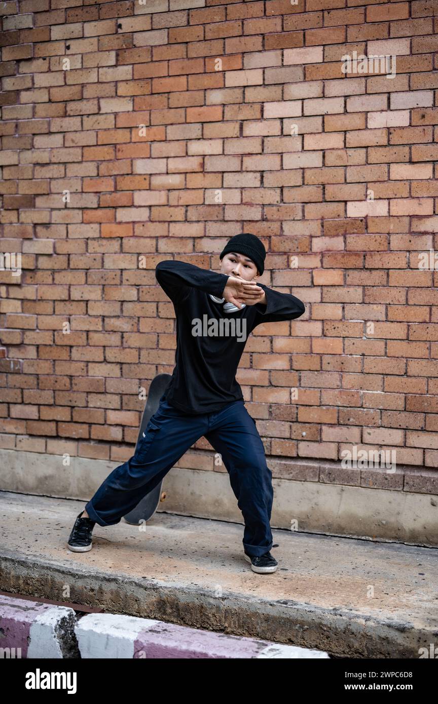 A cool and talented Asian man in fashionable clothes is dancing on the ...