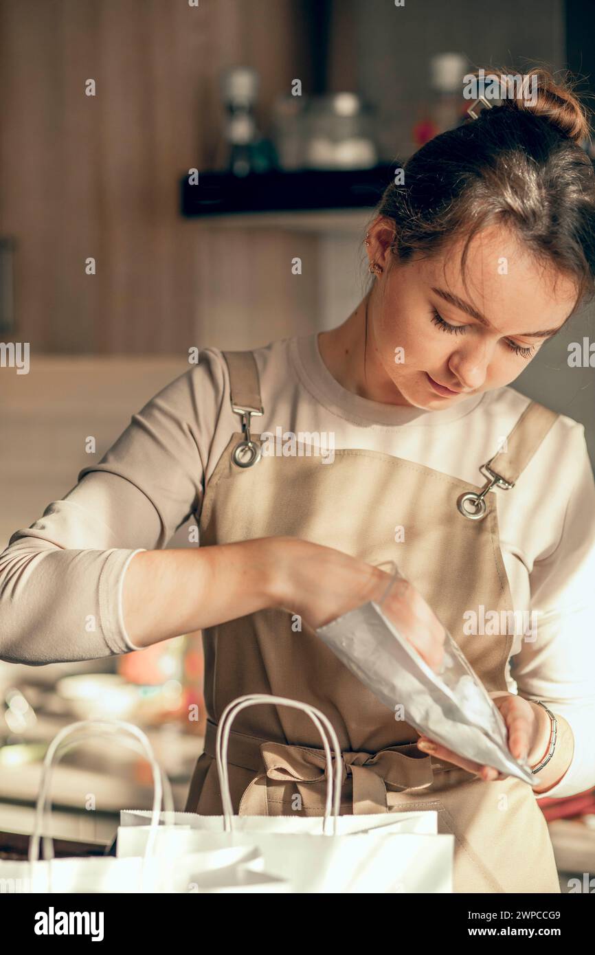 woman bakery shop owner pours confetti into a bag for customer order ...