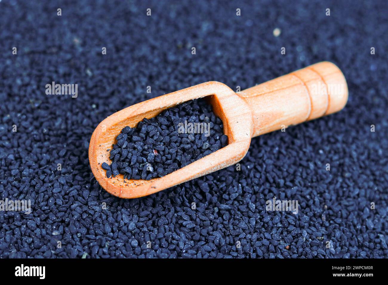 Black Cumin seeds in wooden scoop on Black Cumin background Stock Photo ...