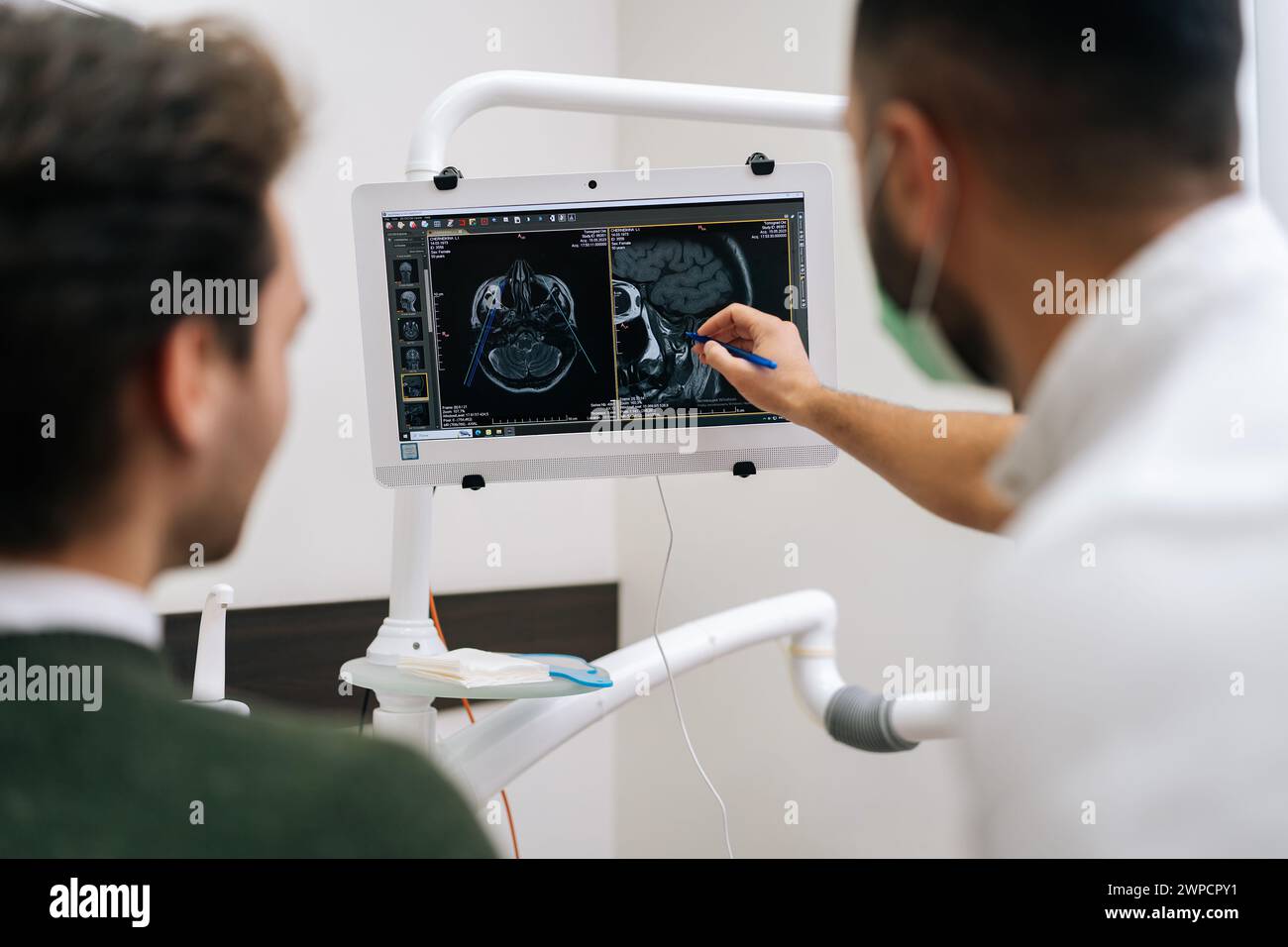Back view of unrecognizable male dentist pointing at teeth radiography ...