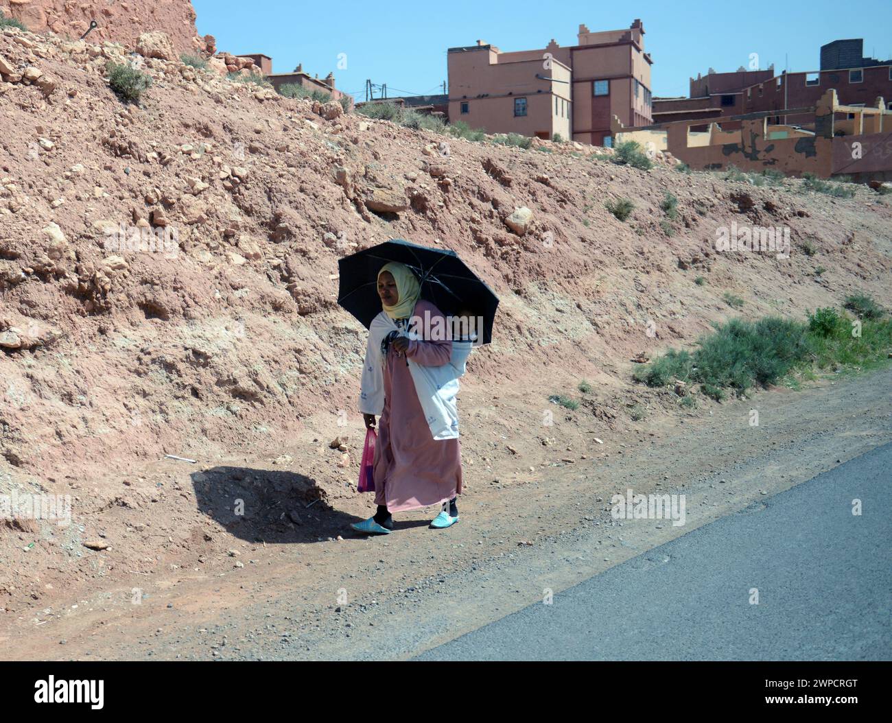 A Berber woman walking along the road to Quarzazate in Morocco Stock ...