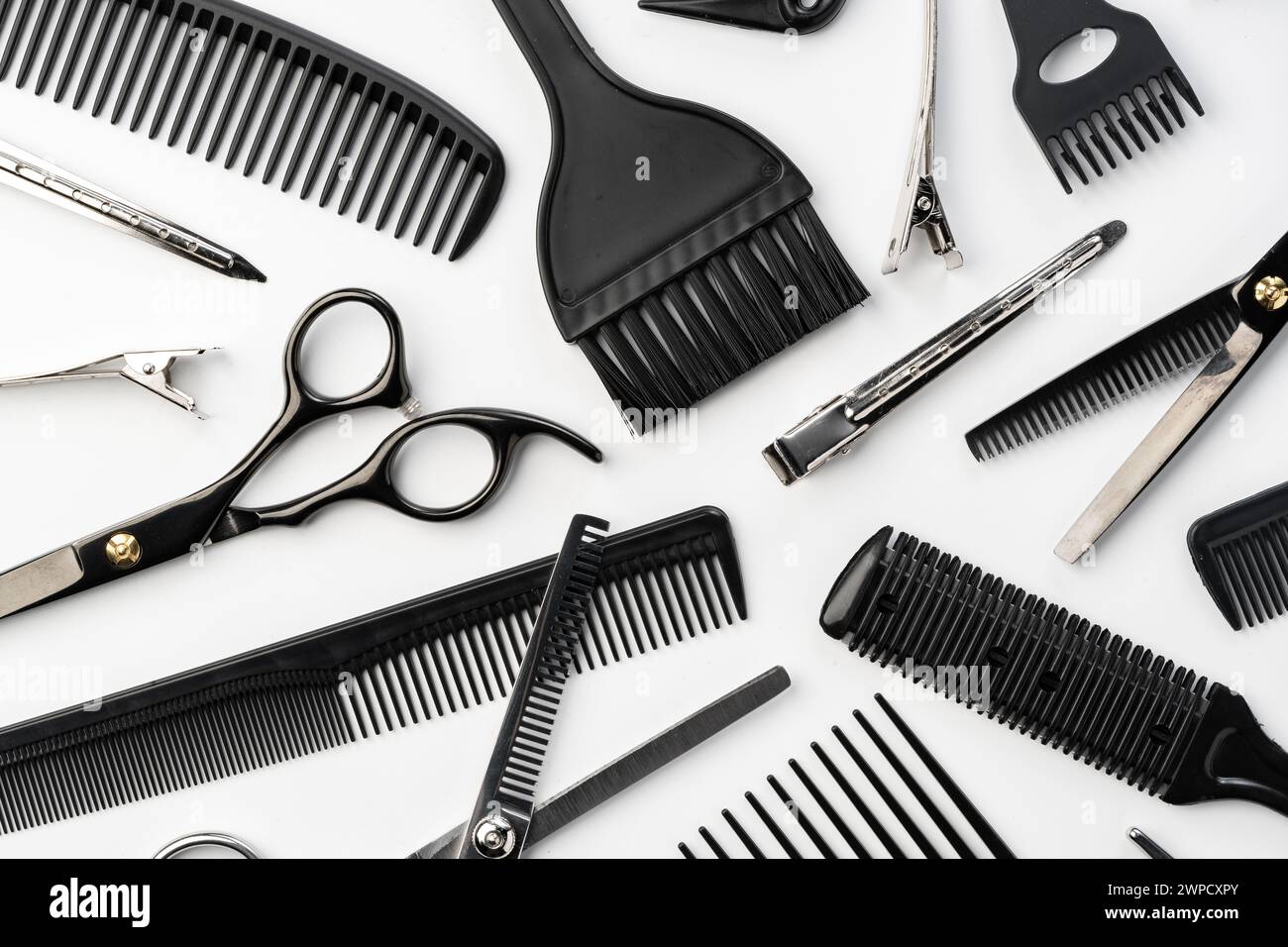 Black hairdressing tools and various hairbrushes on white background ...