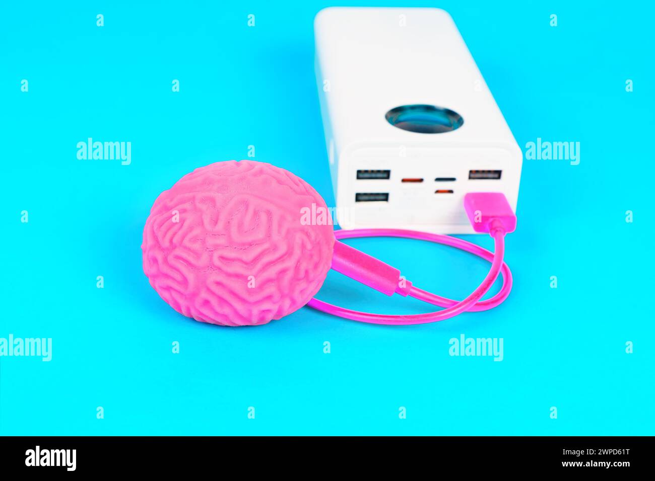 Pink human brain model connected to a power bank isolated on blue ...