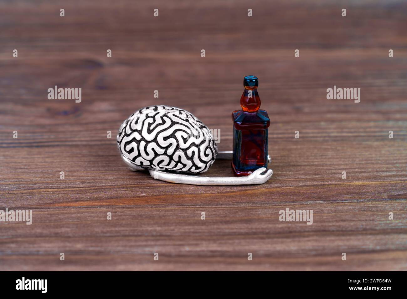 Steel brain with hands gripping a whiskey bottle against a wooden ...