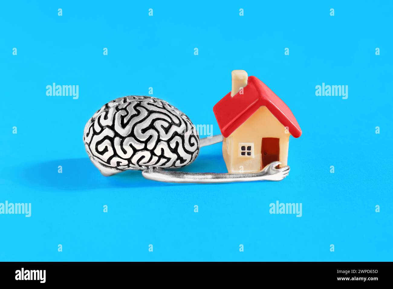 Close-up view of a steel model of a human brain cradling a toy house in ...