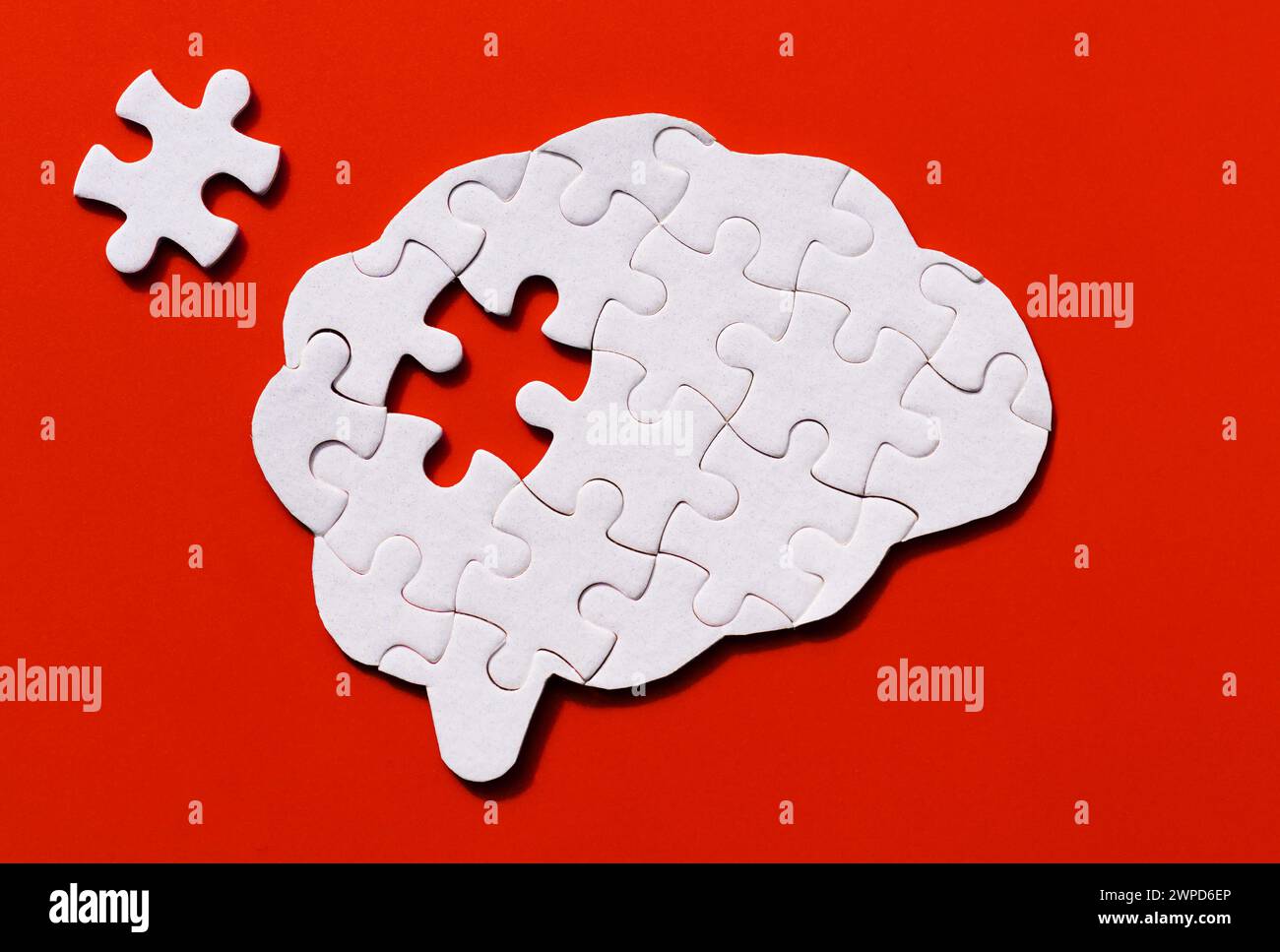 Human brain-shaped puzzle missing a crucial piece lying beside it on a ...