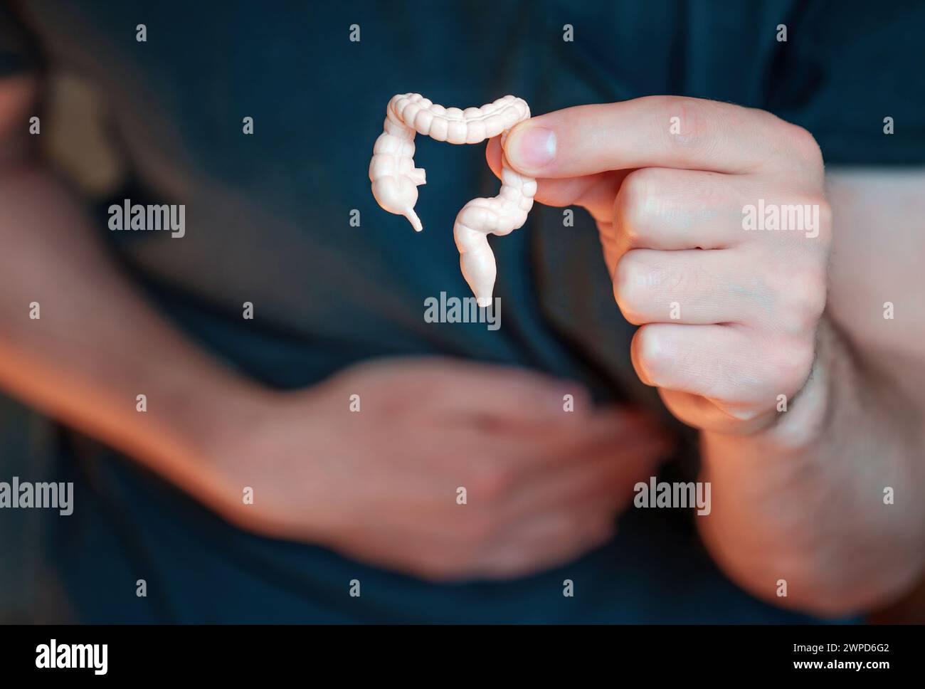 Close-up shot of a man doubled over in agony, clutching his abdomen ...