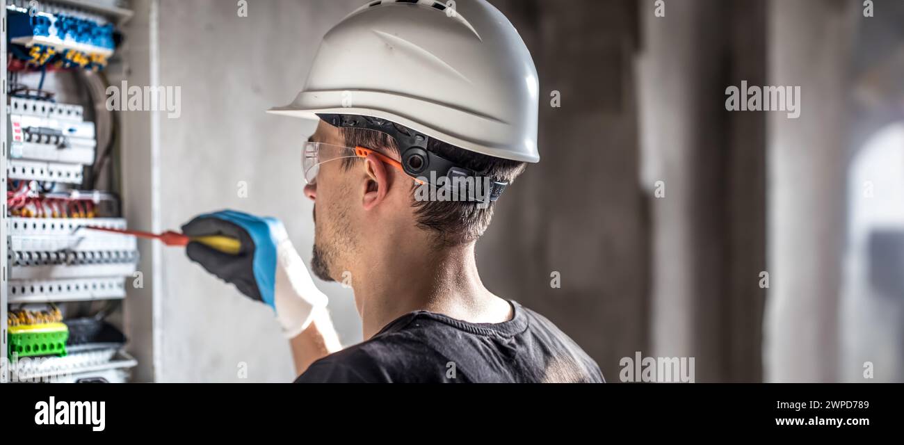 Male electrician working in switchboard with electrical connection ...