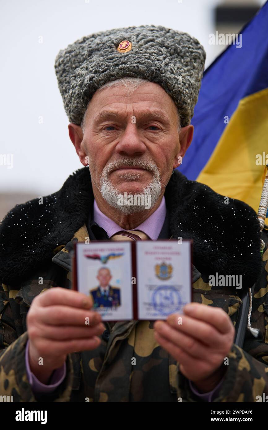 Senior soldier in traditional kozak hat proudly shows the Ukrainian ...