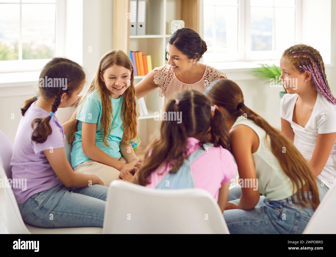 School psychologist woman having conversation with group of children ...