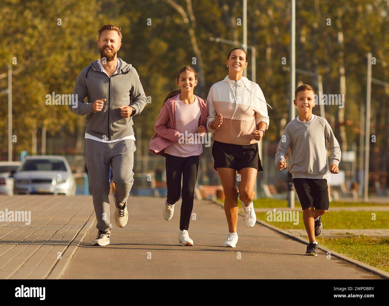 Active parents with their children do sports by running together in ...