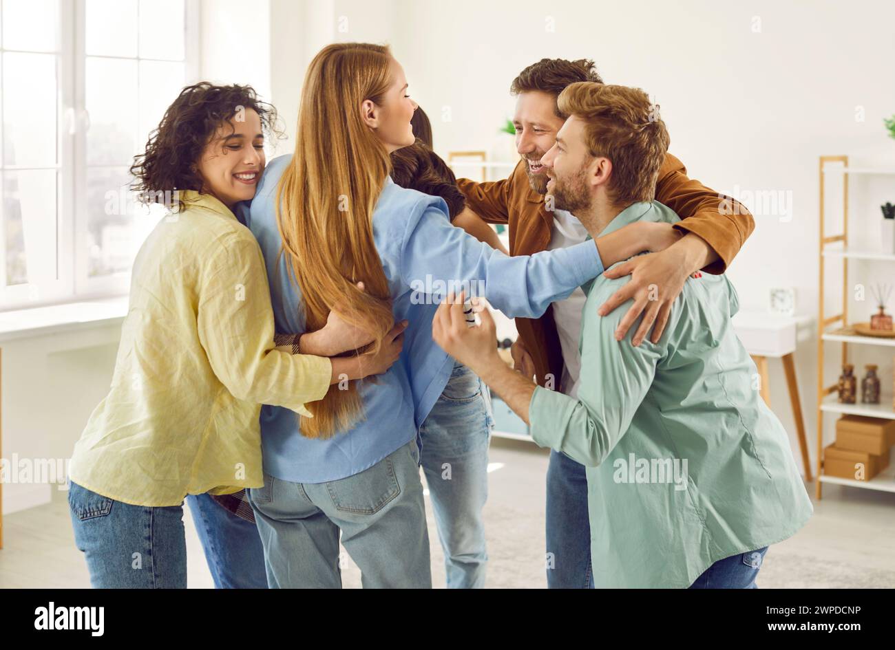 Group of happy laughing friends hugging indoors and enjoying spending ...