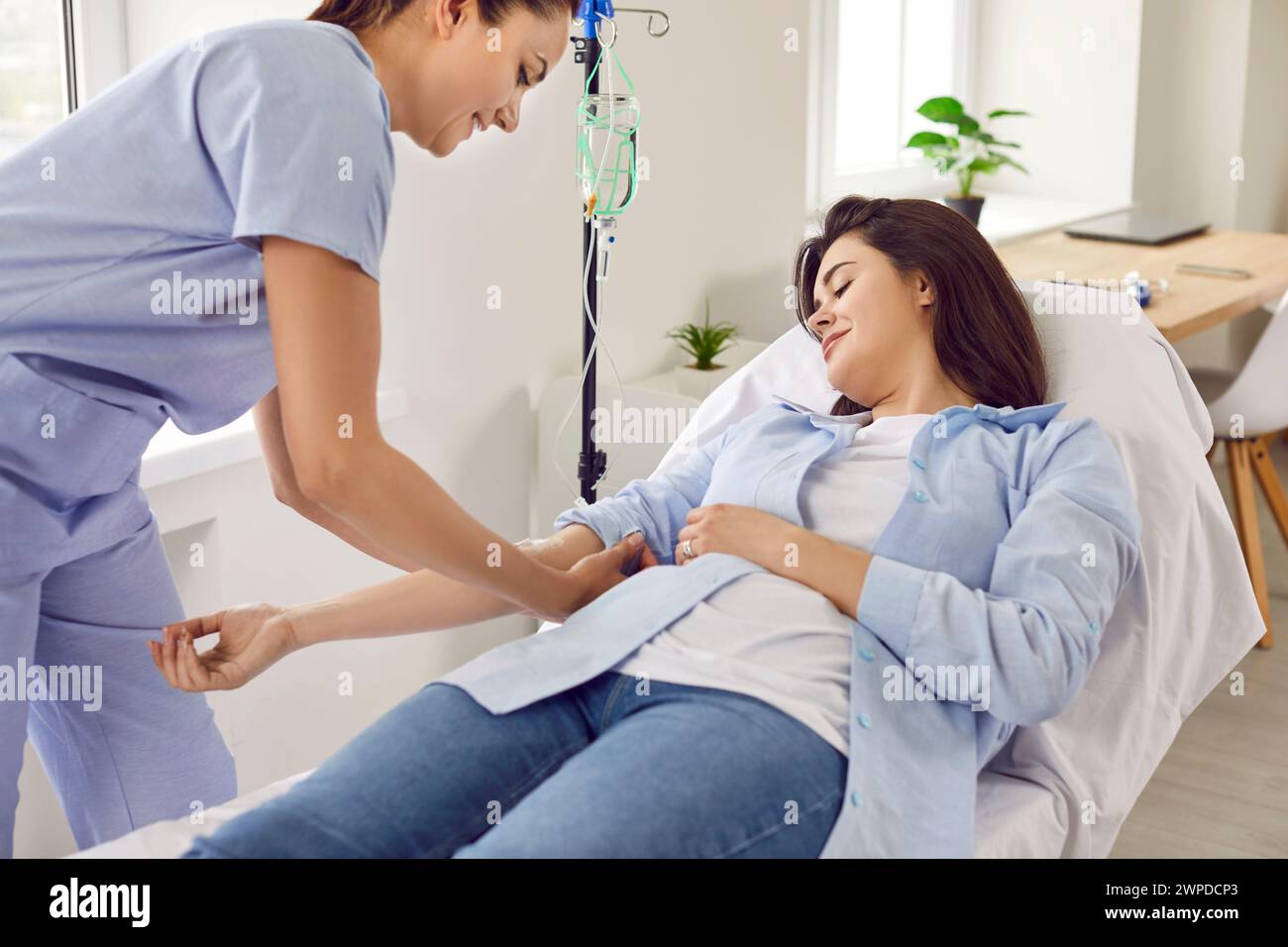 Young nurse making IV drip infusion or vitamin therapy to a pregnant ...
