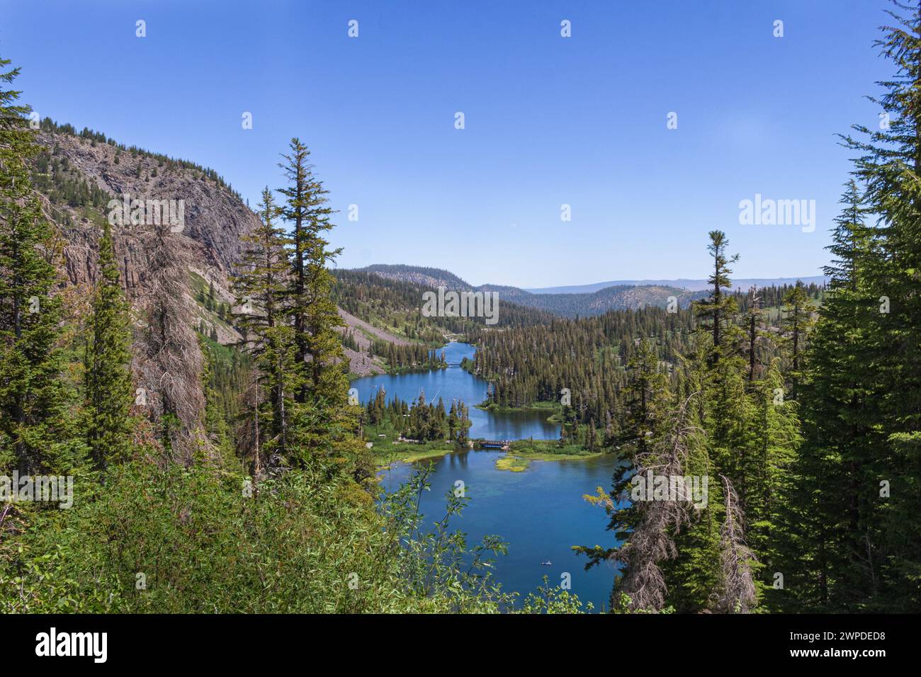 A vast lake nestled in a valley, encircled by towering mountains and ...