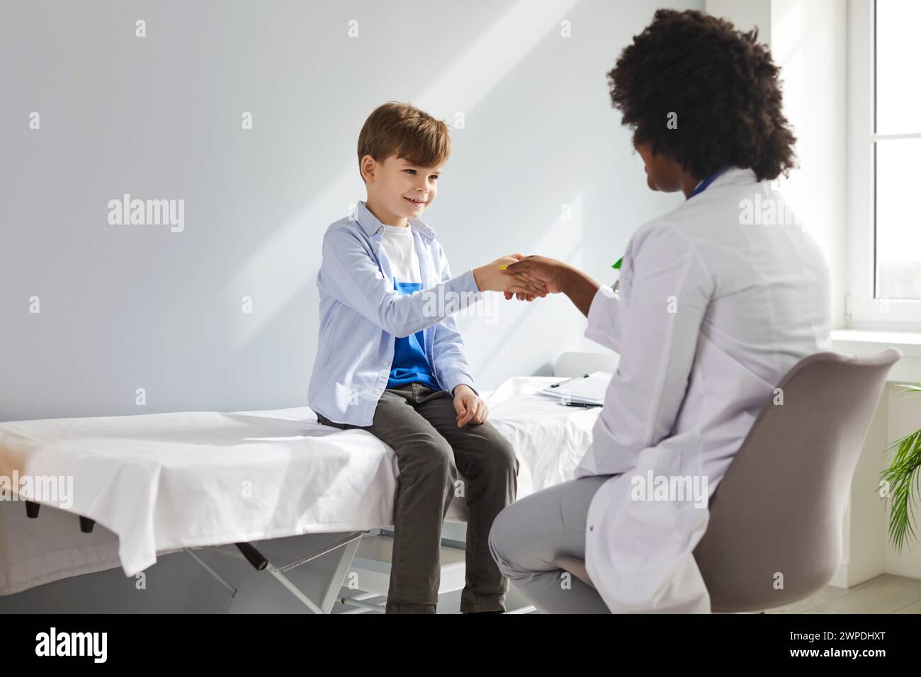 Female African American doctor shaking hands with boy patient Stock ...