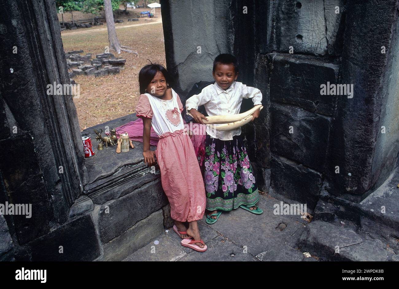 Young girls selling souvenirs near window, Baphoun temple, Angkor Wat ...