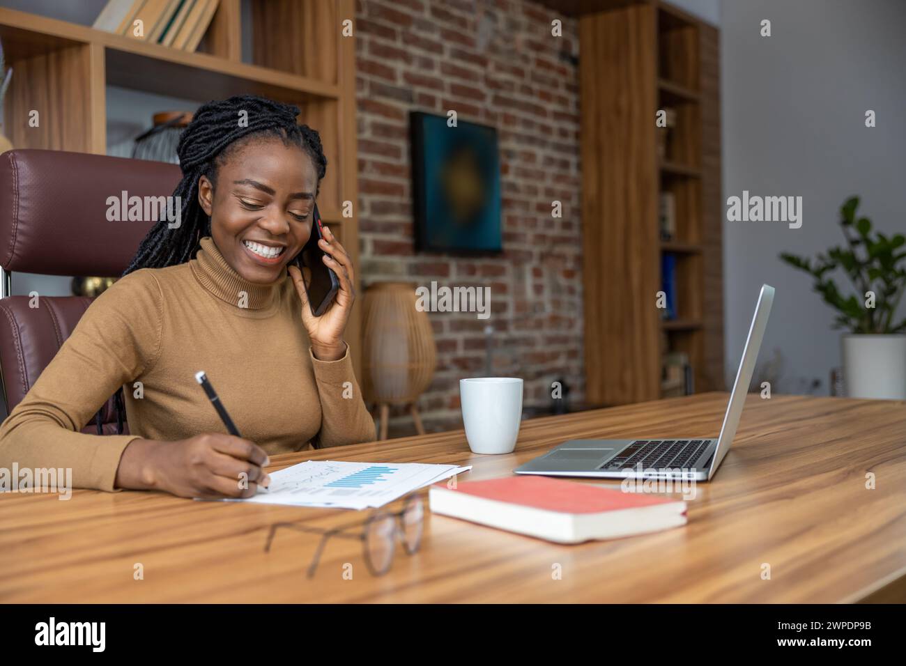 Woman with dreadlocks working with laptop and smartphone manages ...