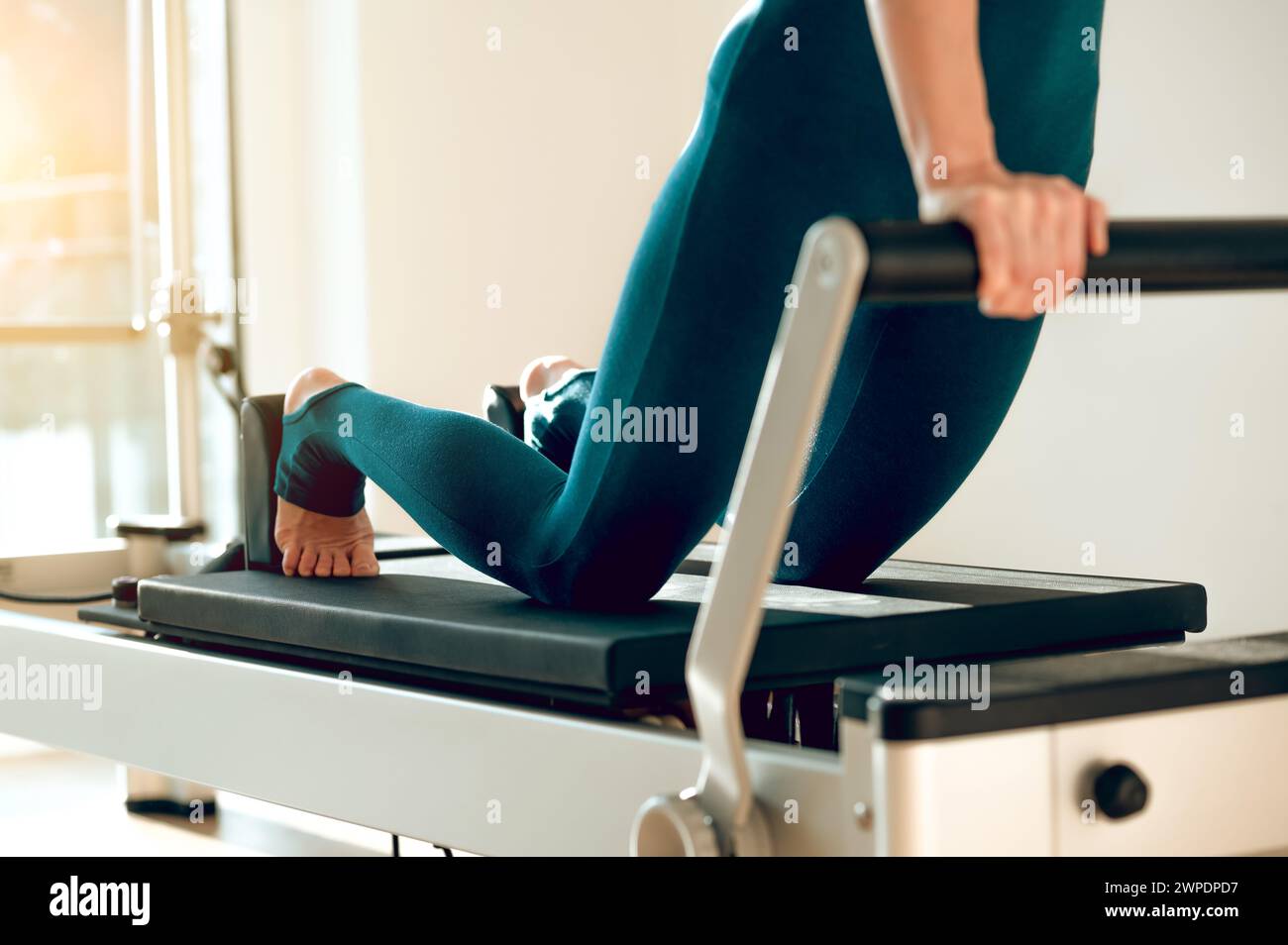 Fit woman using Pilates reformer with flexibility and grace Stock Photo ...