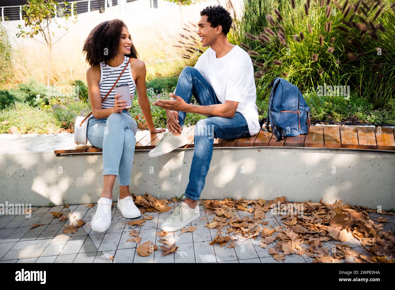 Photo of cheerful nice people best friends sitting on bench speaking ...