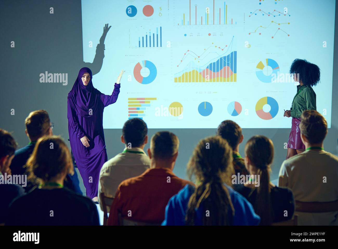 Speaker in hijab raising hand to emphasize point during presentation ...