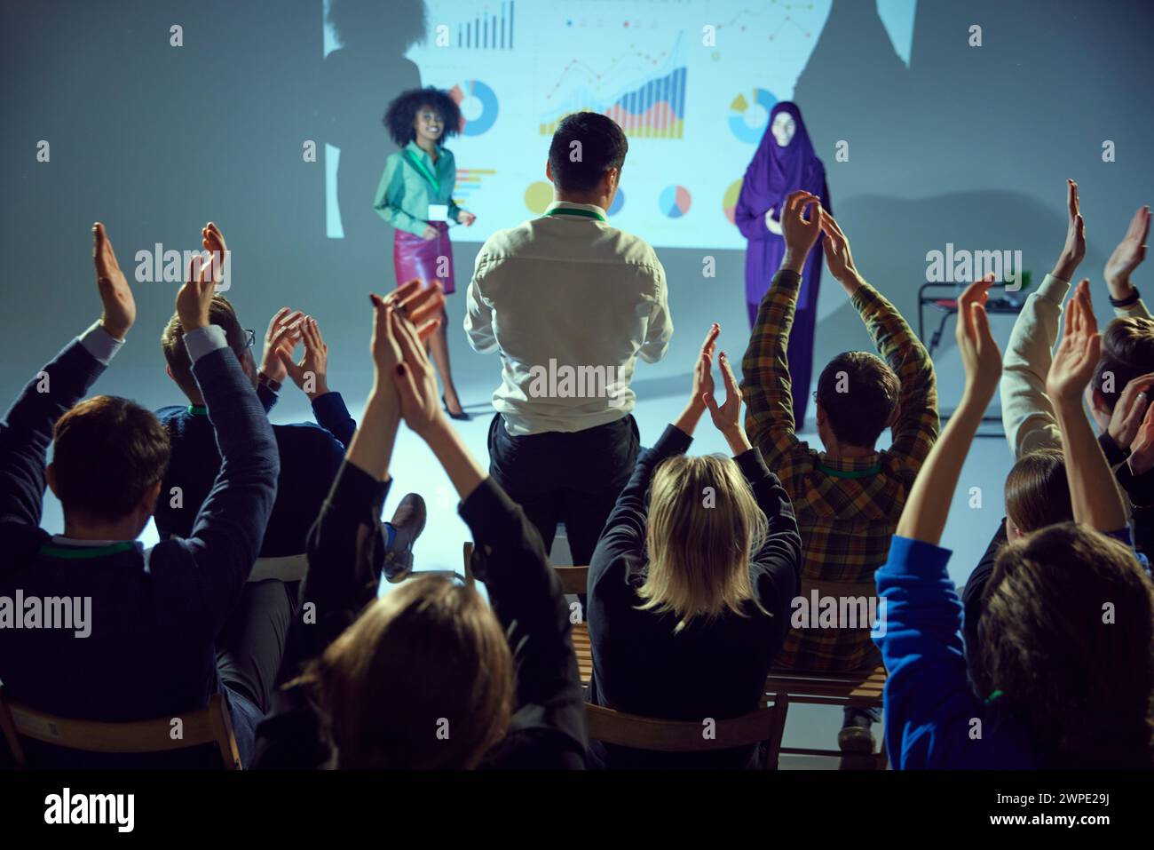 Audience members with raised hands participating in questions and ...