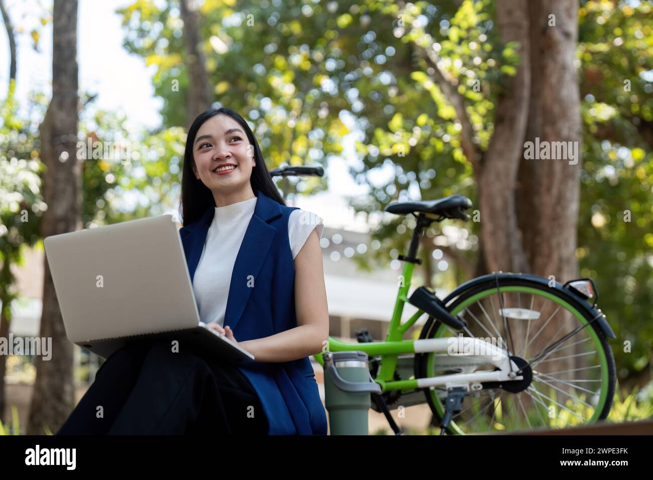 Asian businesswoman with bicycle using laptop and sitting outside the ...