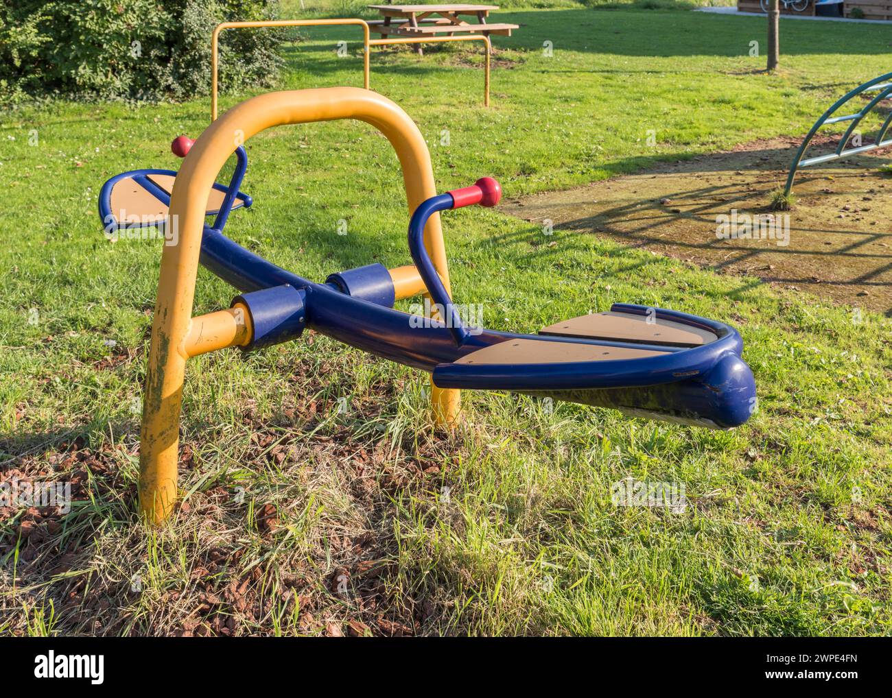 An empty colourful seesaw for kids stands in an outdoor playground with ...