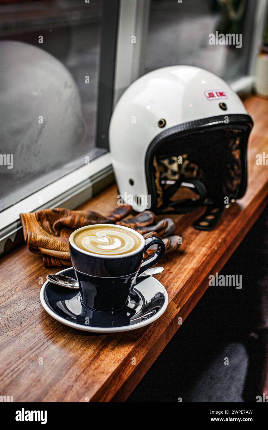 motorcycle helmet with a pair of leather gloves at a cafe next to a cup ...